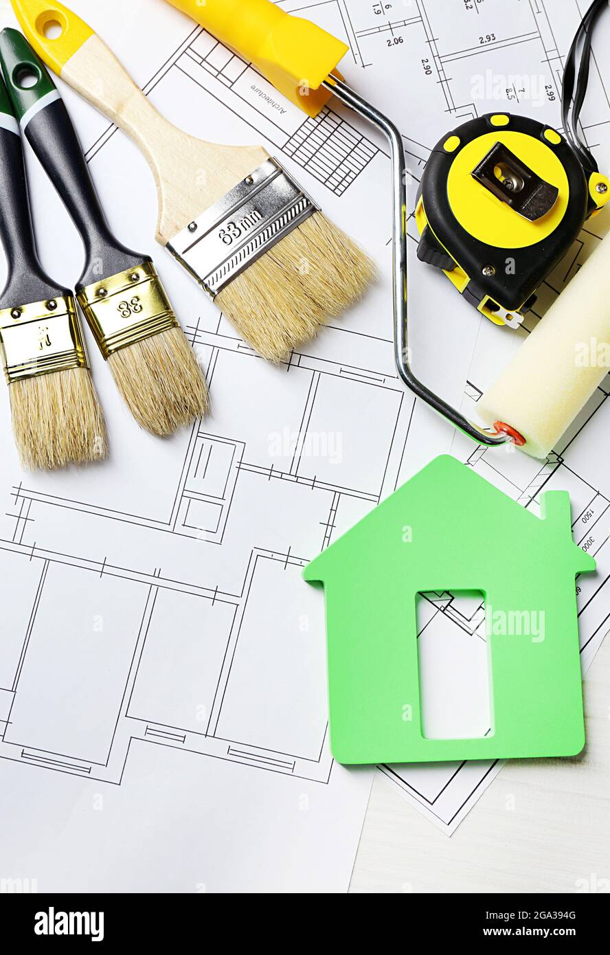 Construction instruments, plan and brushes on wooden table background ...