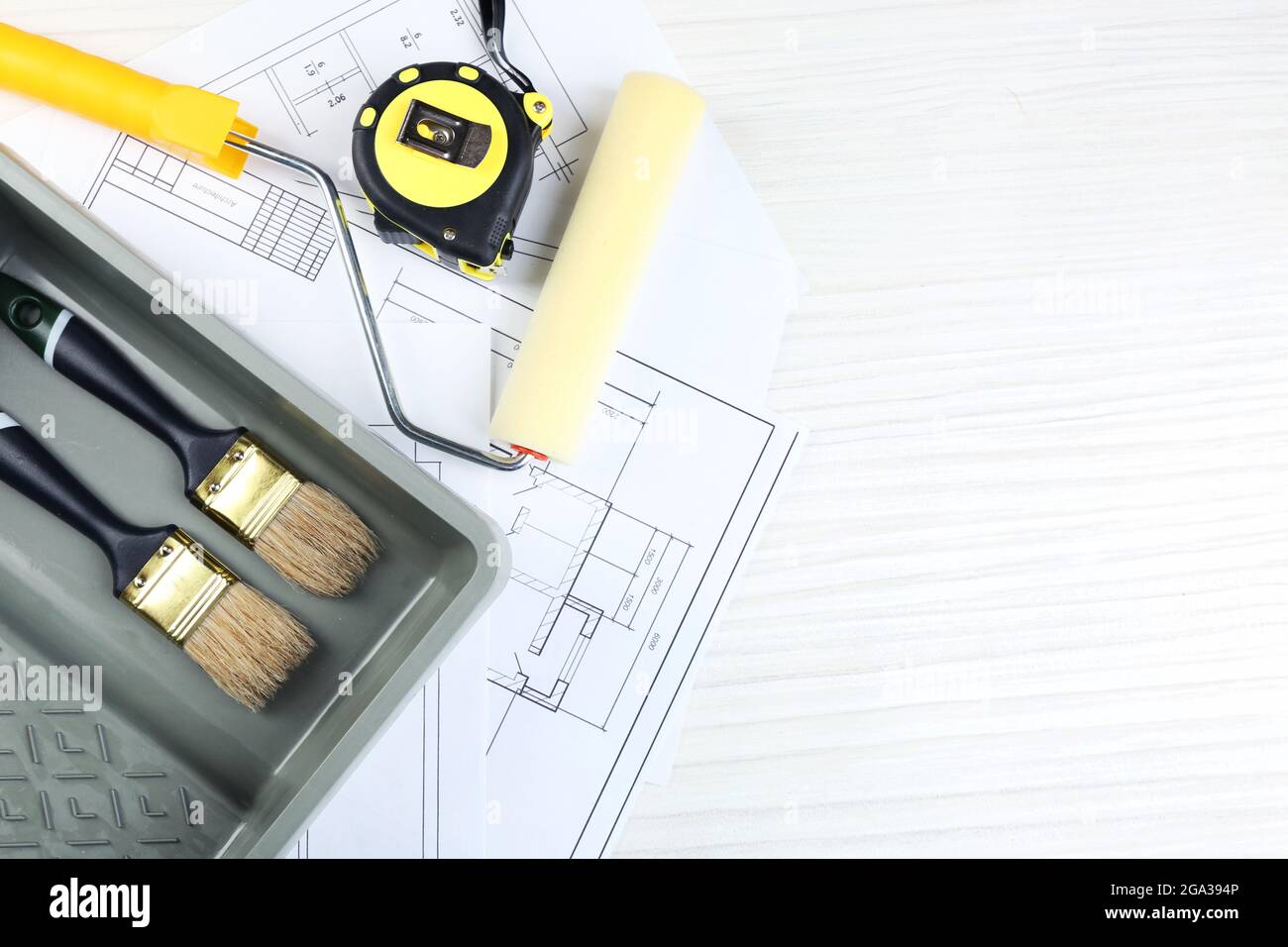 Construction instruments, plan and brushes on wooden table background ...