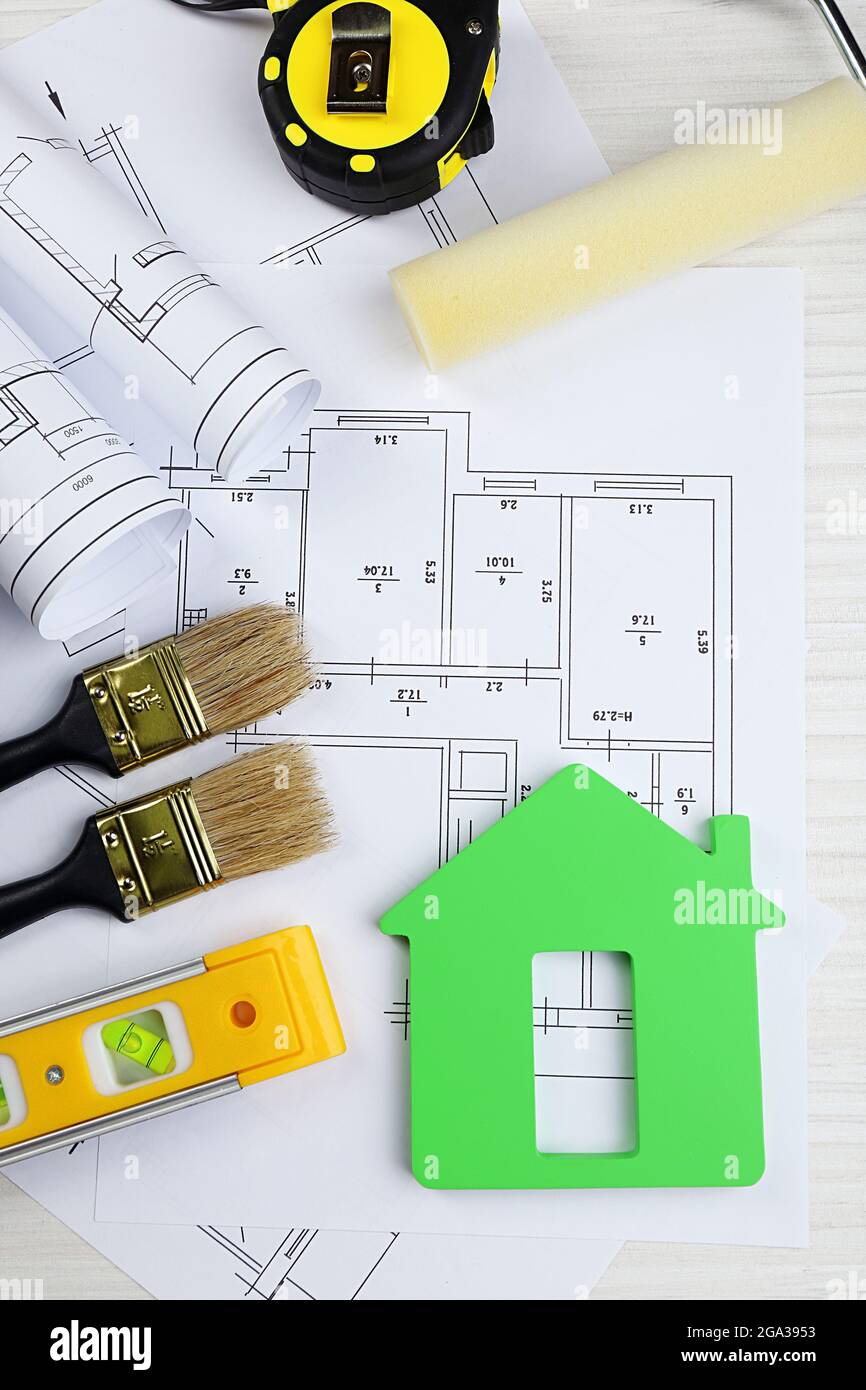 Construction instruments, plan and brushes on wooden table background ...