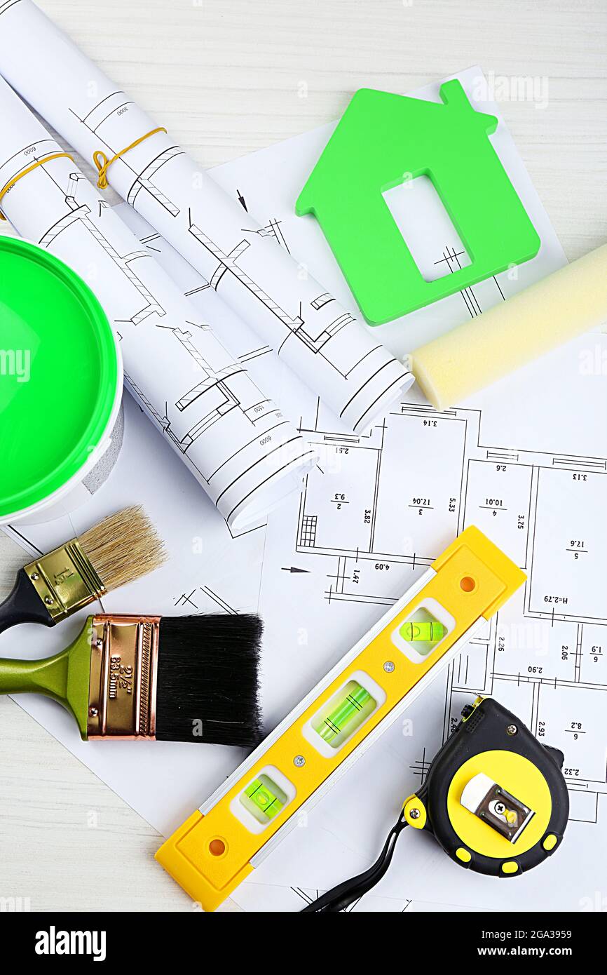 Construction instruments, plan and brushes on wooden table background ...