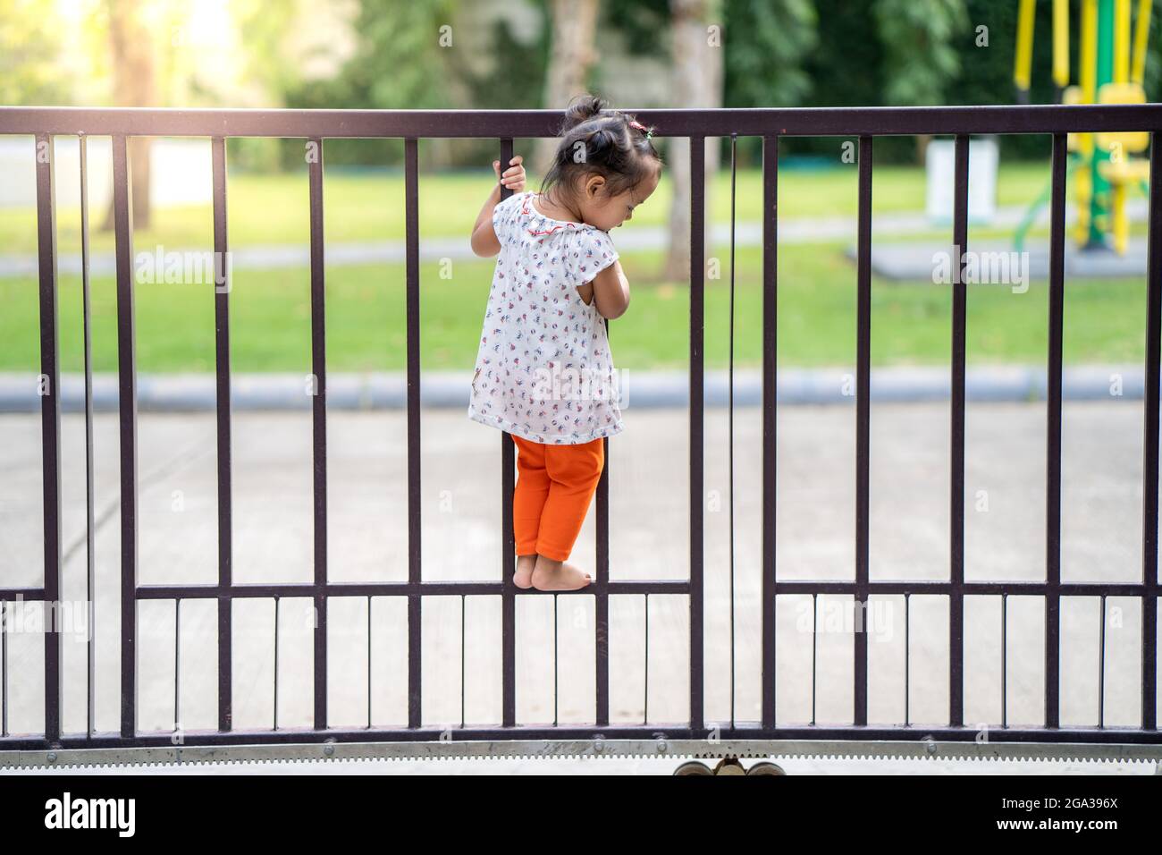 Cute Asian female child playing on a gate Stock Photo - Alamy