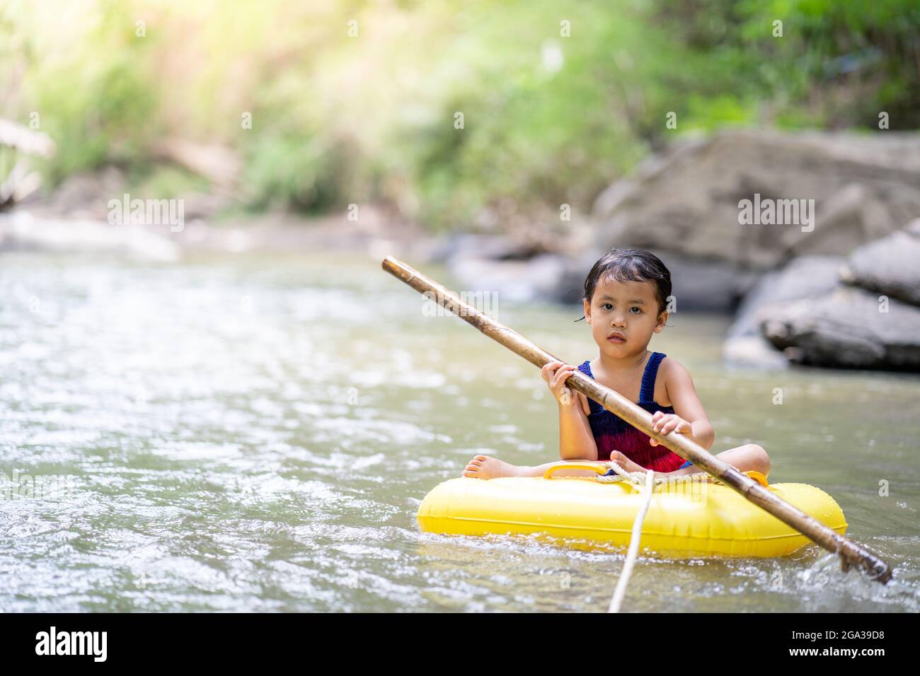 Asian cute female child rowing in a yellow raft Stock Photo - Alamy