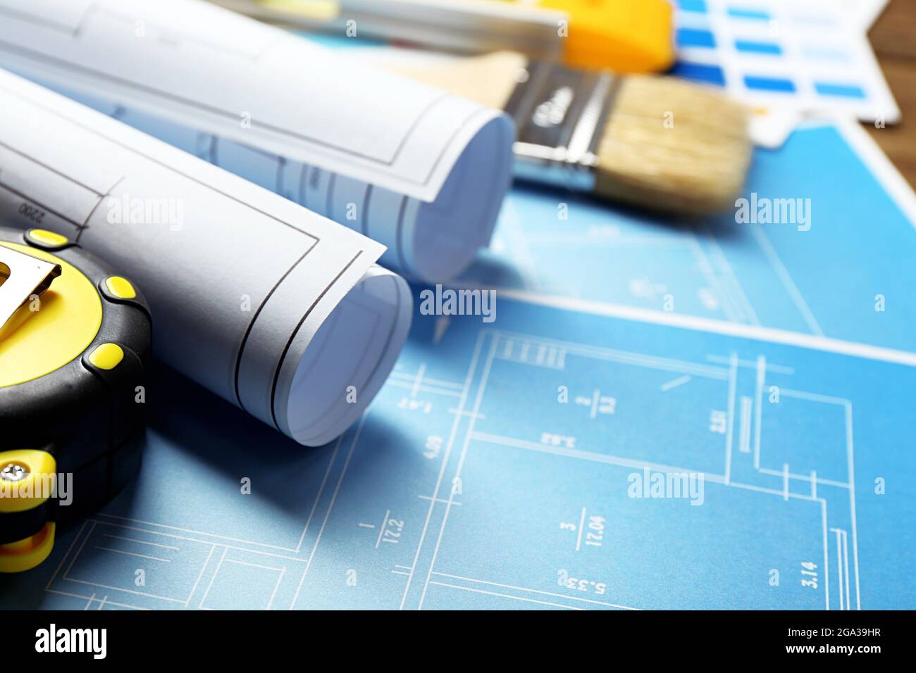 Construction instruments, plan and brushes on wooden table background ...