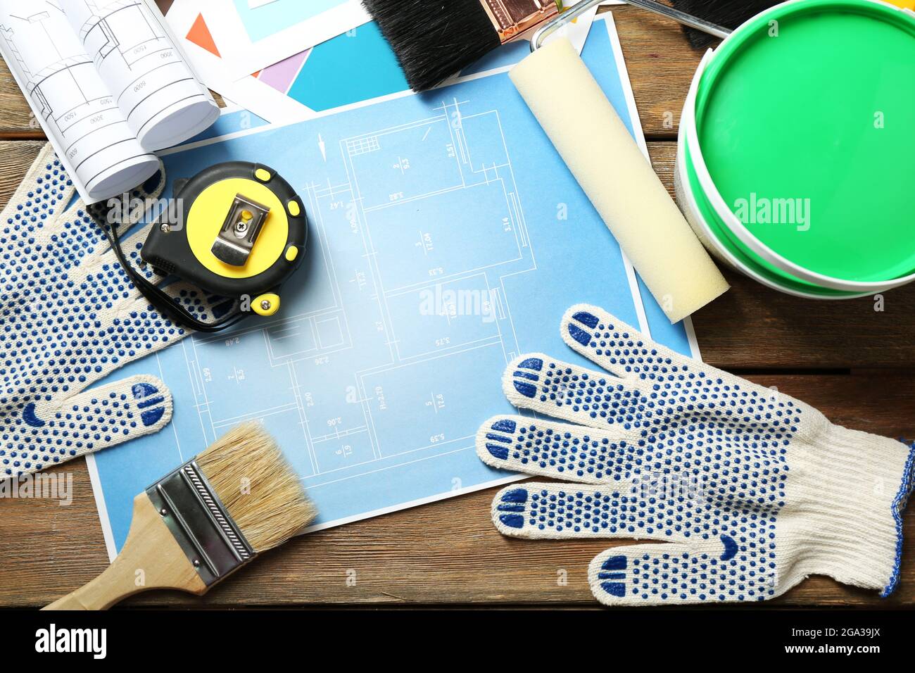 Construction instruments, plan and brushes on wooden table background ...