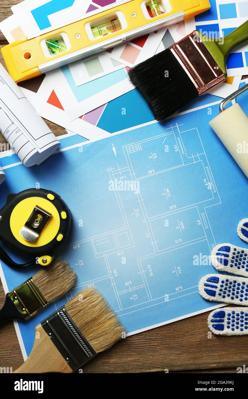 Construction instruments, plan and brushes on wooden table background ...