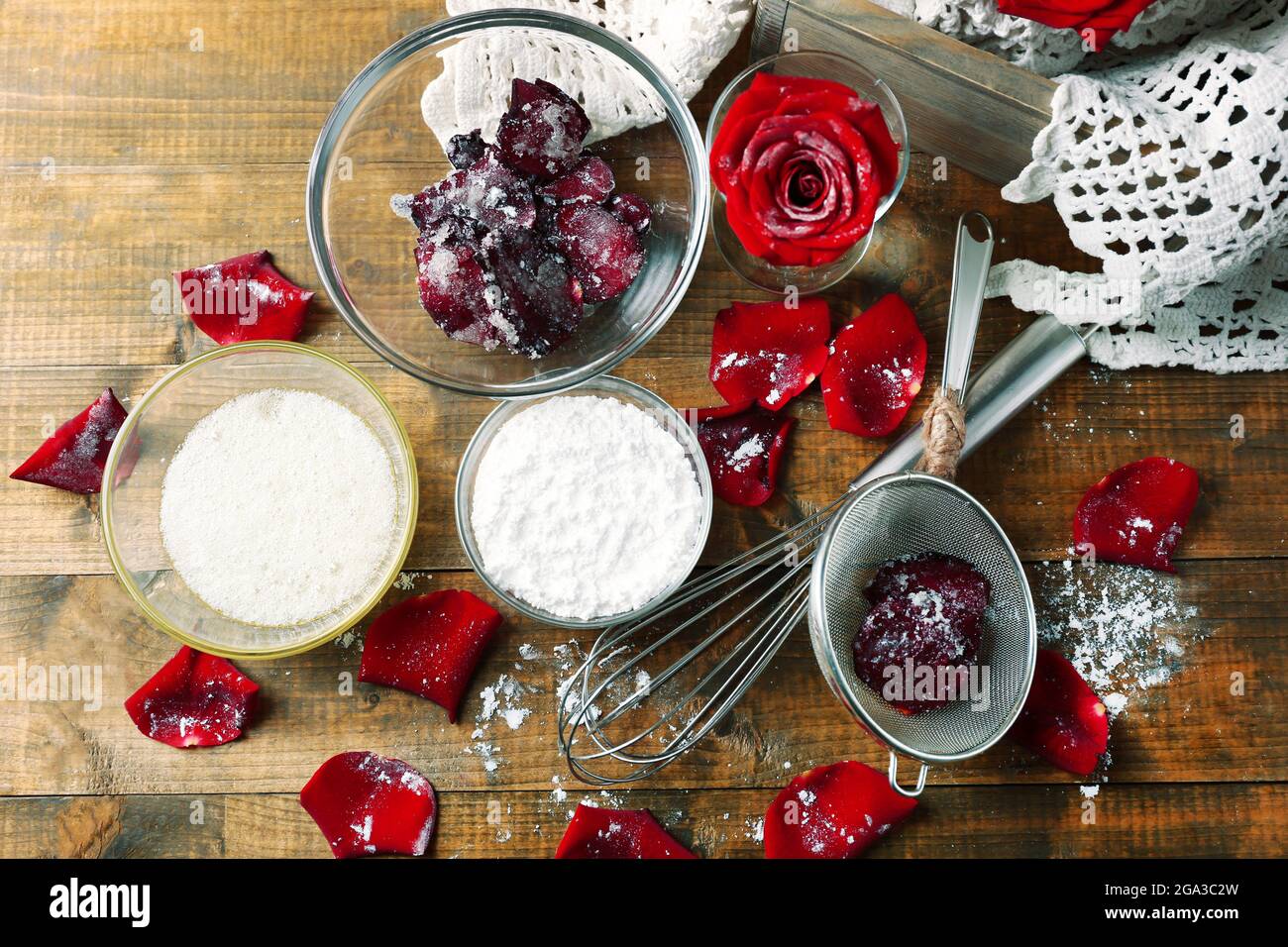 Making candied rose flower petals with egg whites and sugar, on wooden ...
