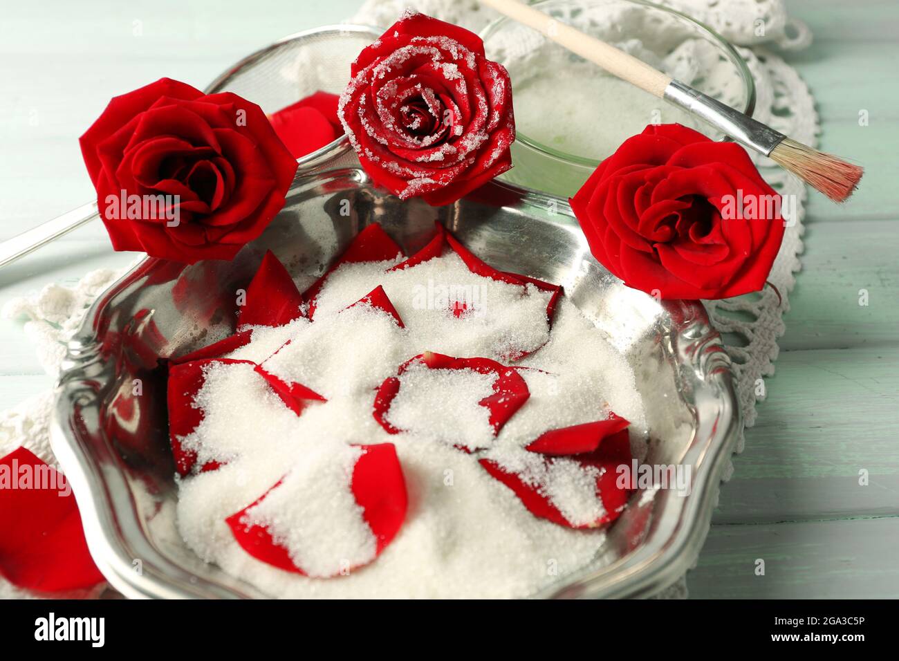 Making candied rose flower petals with egg whites and sugar, on wooden ...