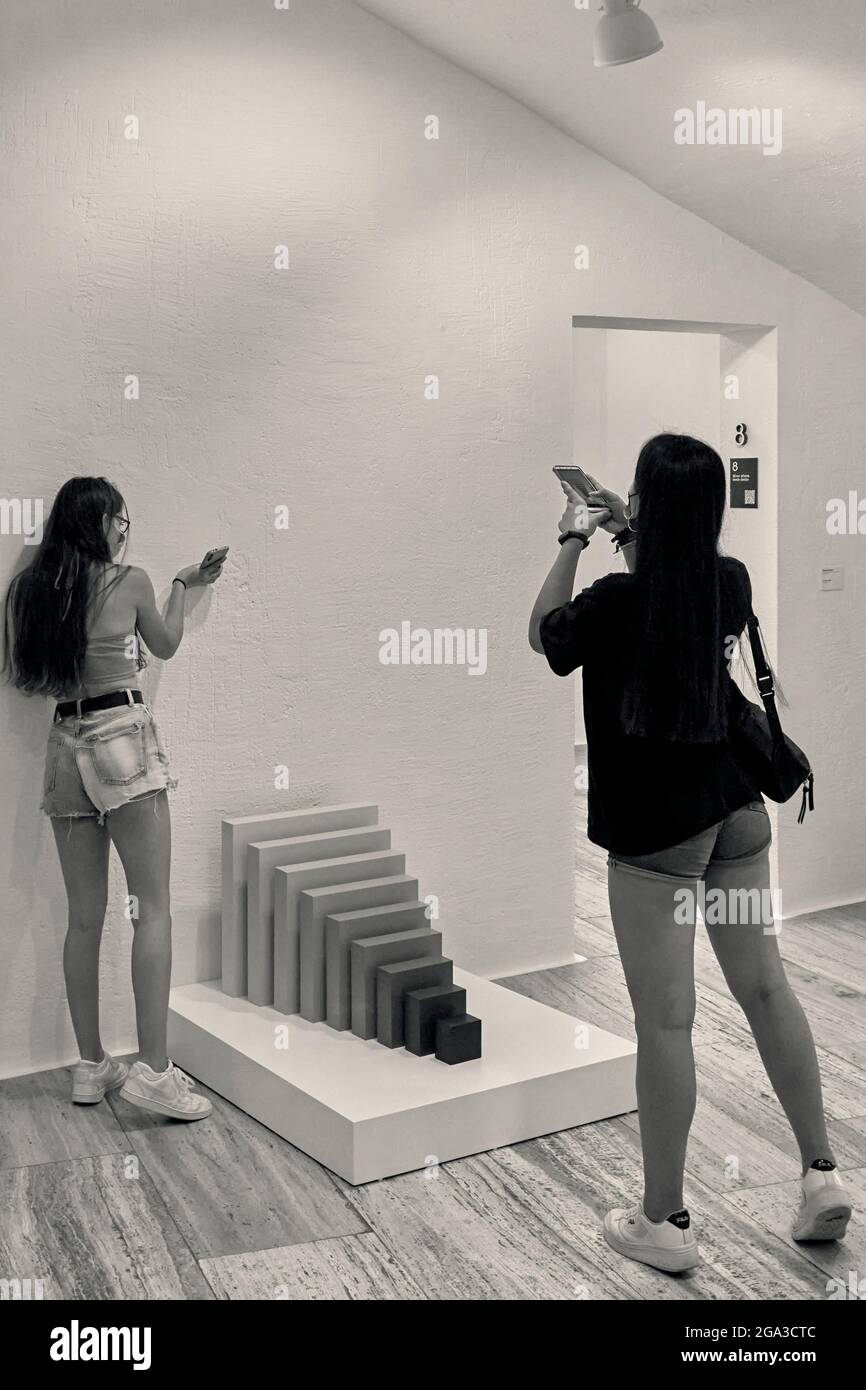 Two young girls taking a photo of a sculpture in the museum of Spanish ...