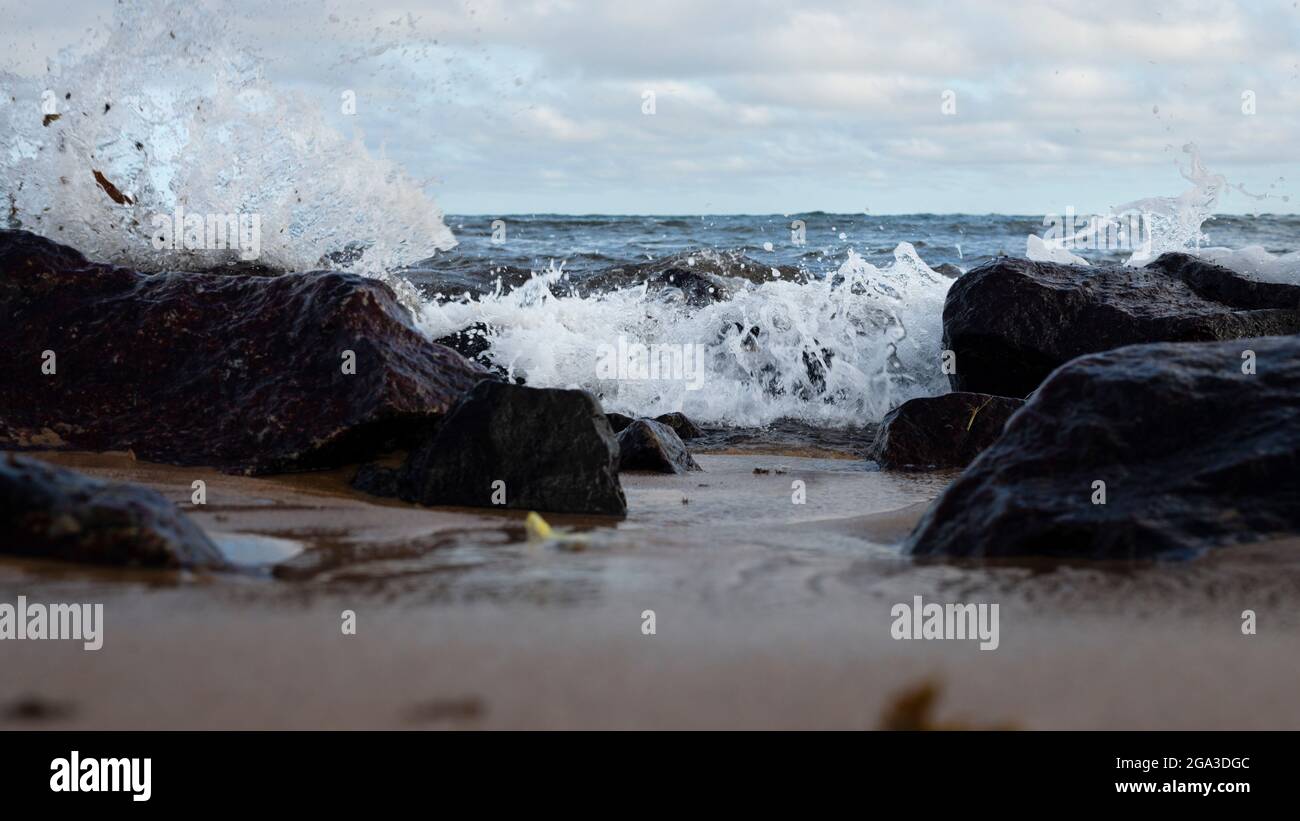 Blue sky and sea over the rocks and sand on the beach. Waves crashing ...