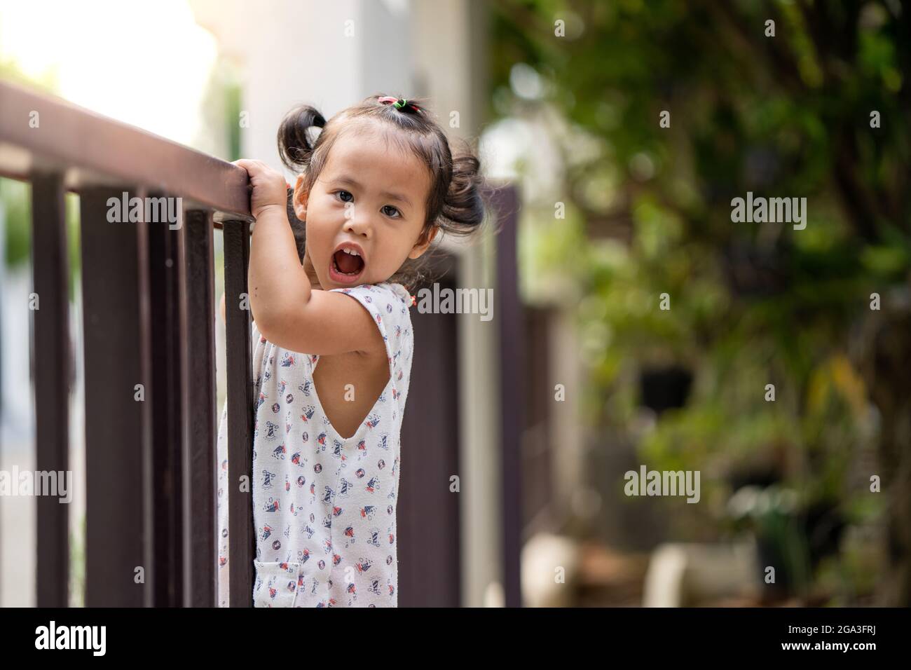 Cute Asian female child playing on a gate Stock Photo - Alamy