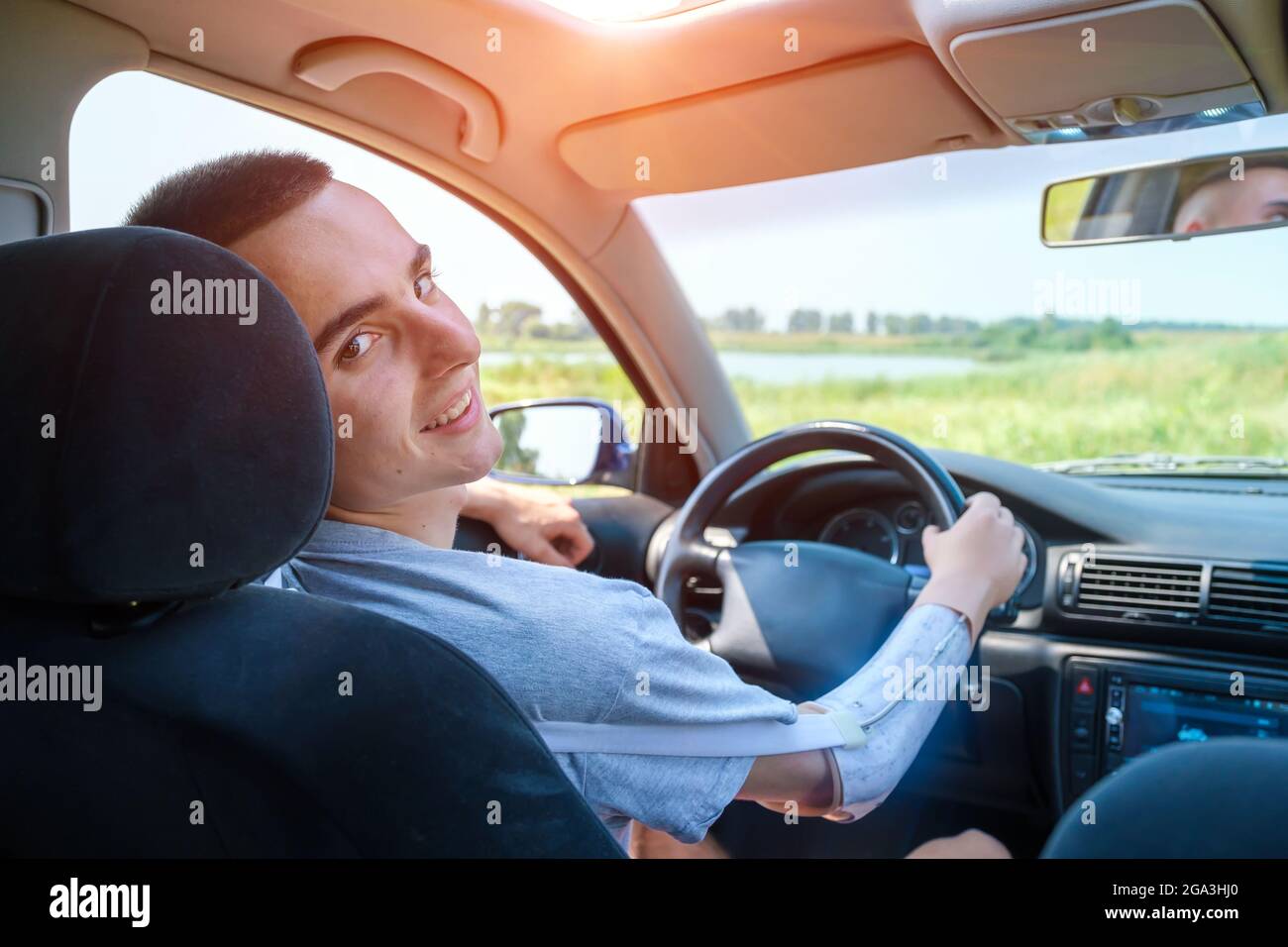 Young caucasian man with an amputated arm drives a car with a ...
