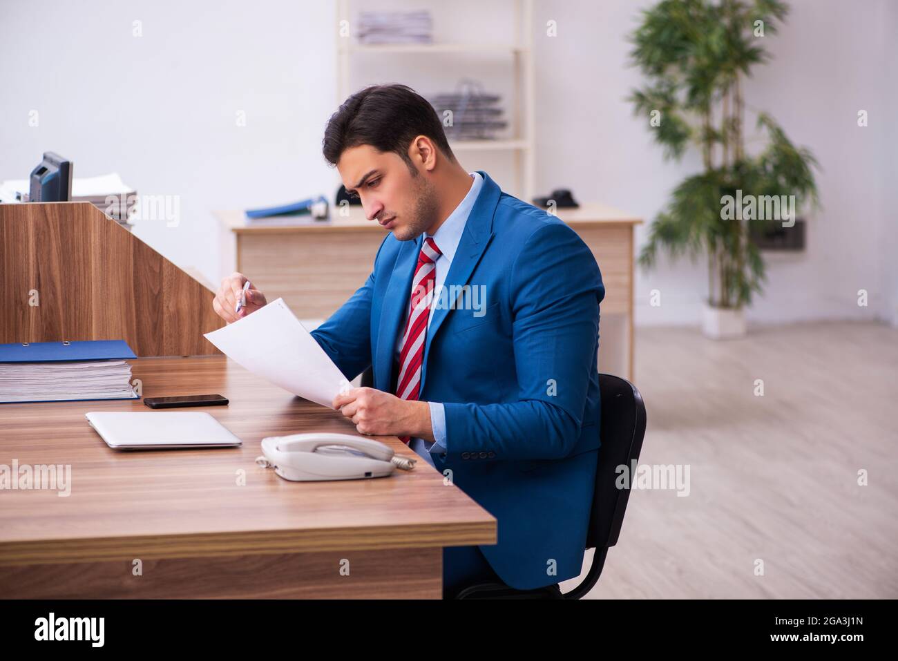 Young male employee working at workplace Stock Photo - Alamy