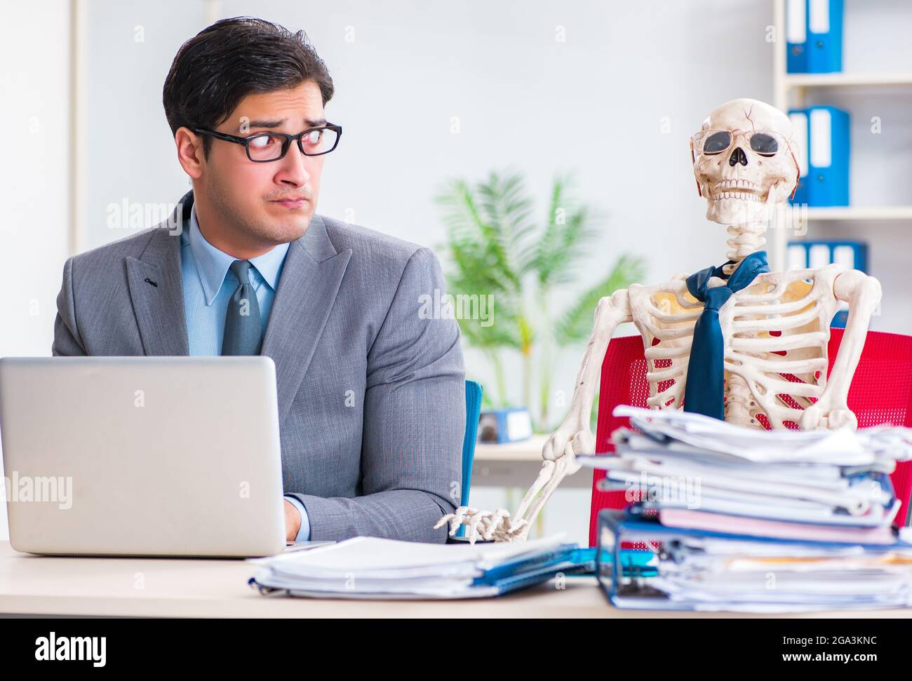 The businessman working with skeleton in office Stock Photo - Alamy