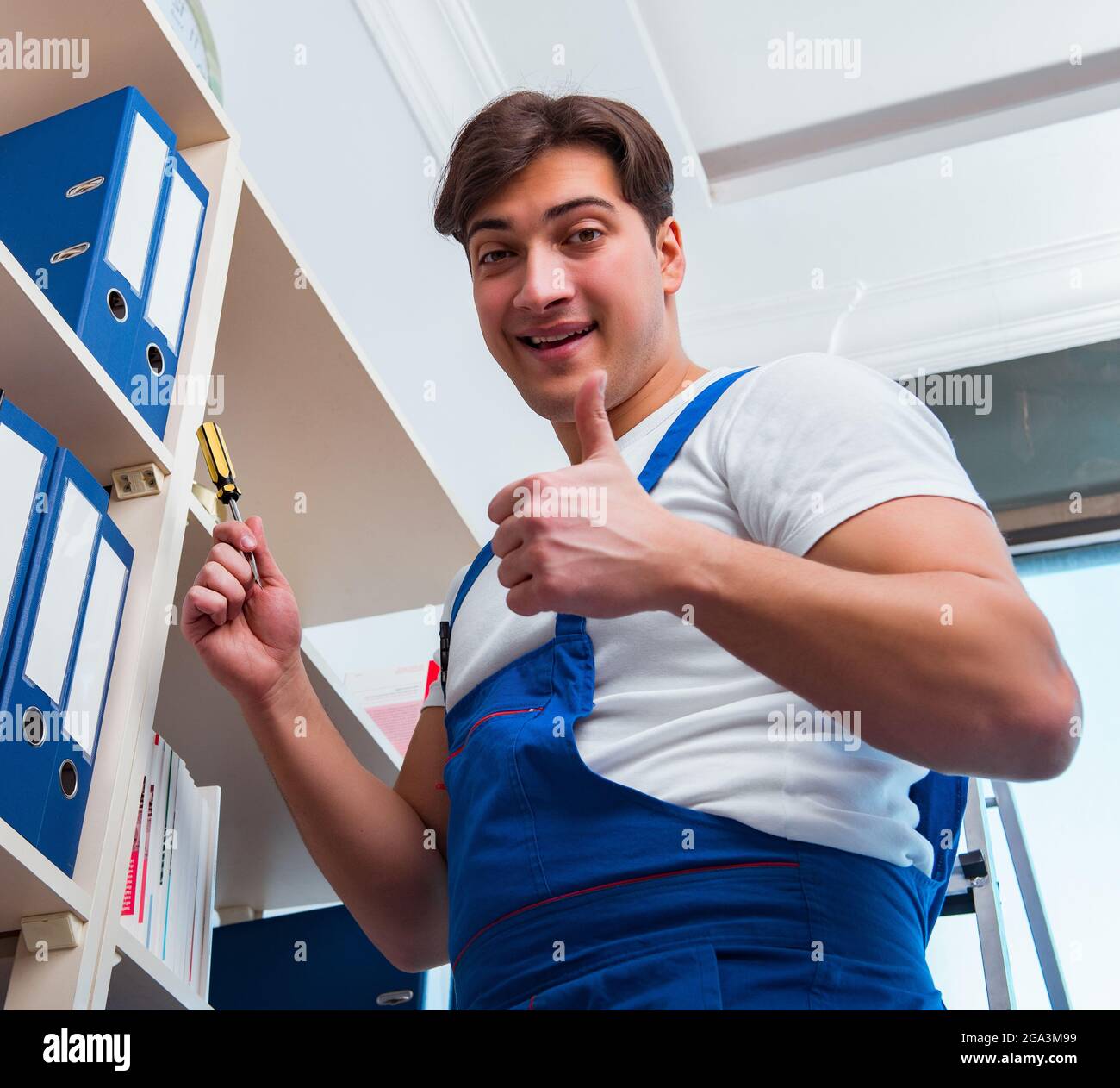The male office cleaner cleaning shelves in office Stock Photo - Alamy