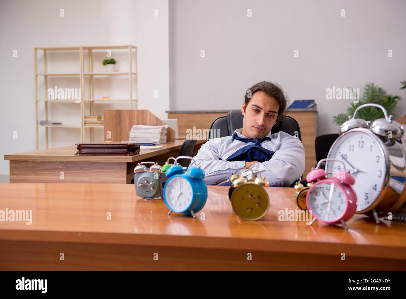 Young businessman sleeping in the office in time management concept ...