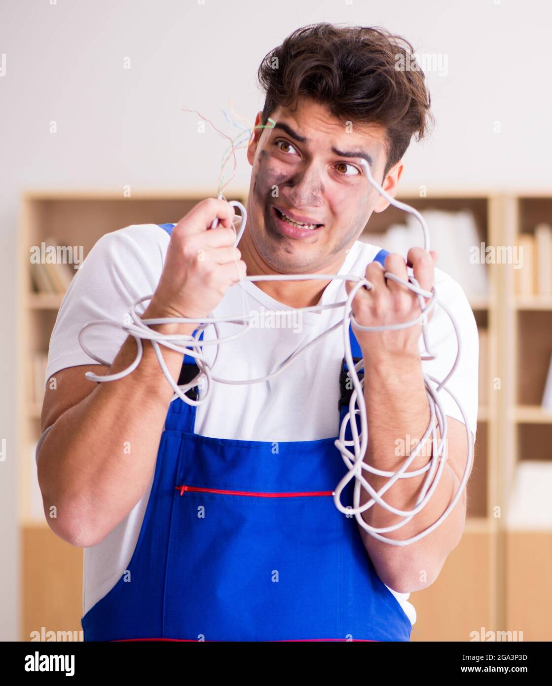 The funny young electrician tangled in cables Stock Photo - Alamy