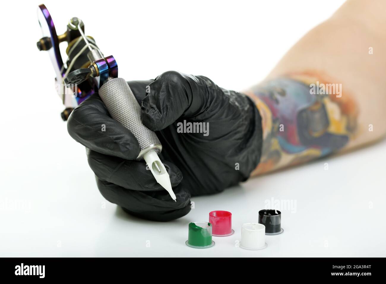 Hand of tattoo artist with tattoo machine and colorful ink isolated on ...