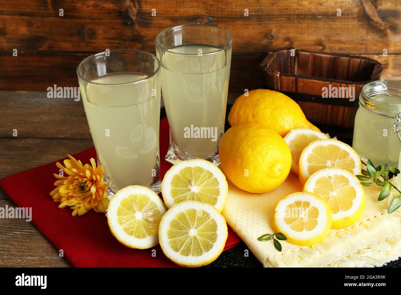 Still life with lemon juice and sliced lemons on wooden background ...