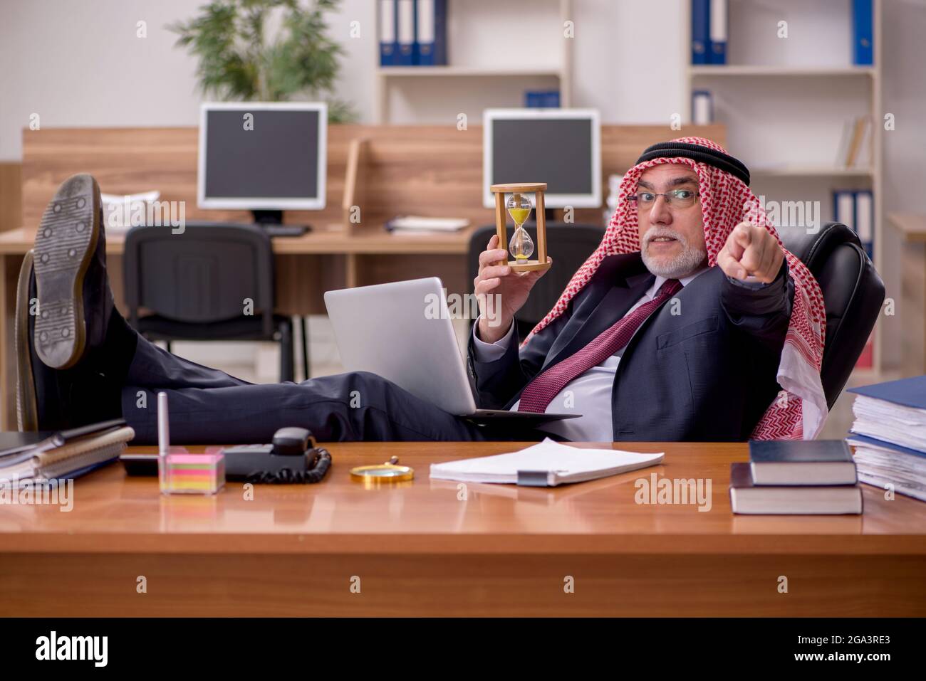 Aged male arab employee in time management concept Stock Photo - Alamy