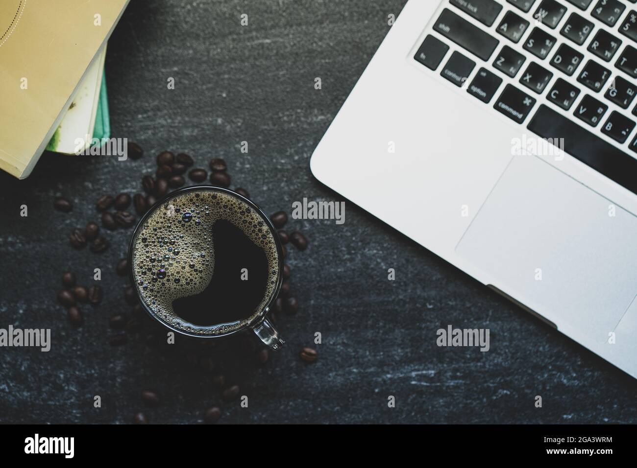 Cup of black coffee with roasted coffee beans next to a laptop computer ...