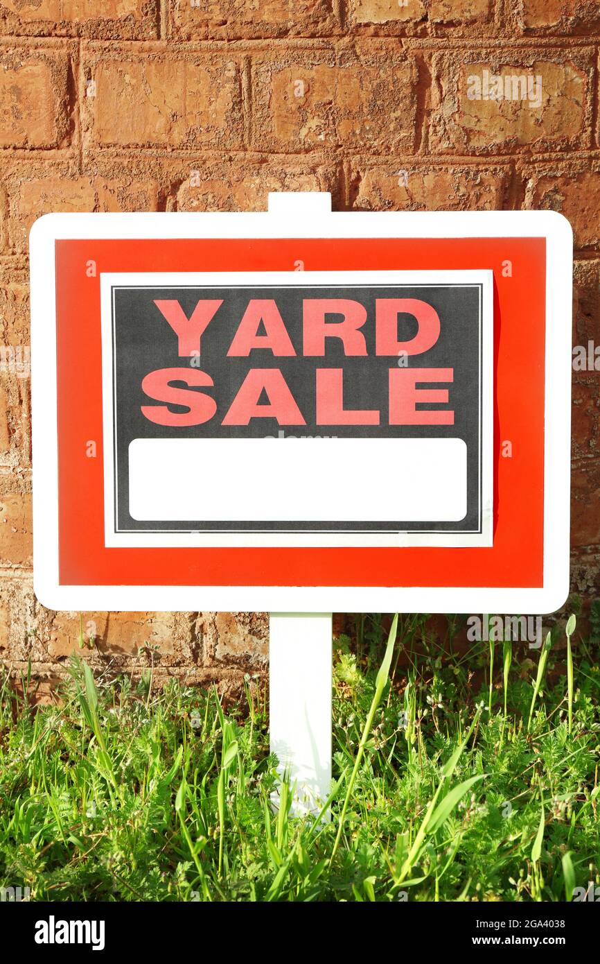 Wooden Yard Sale sign in green grass on red brick wall background Stock ...