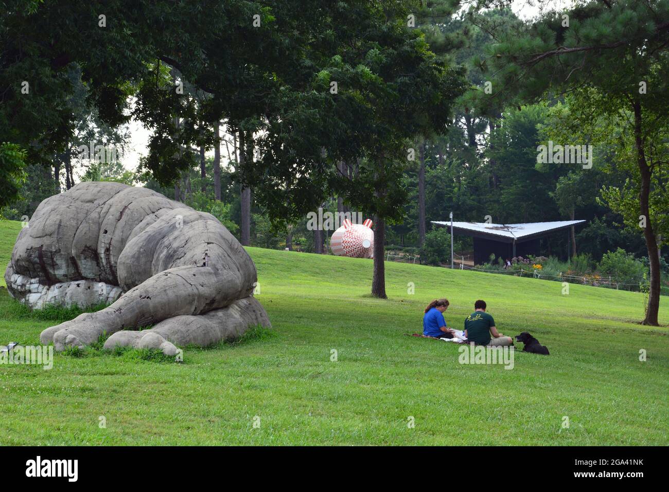 A couple with dog relax next to the sculpture Collapse by Ledelle Moe ...