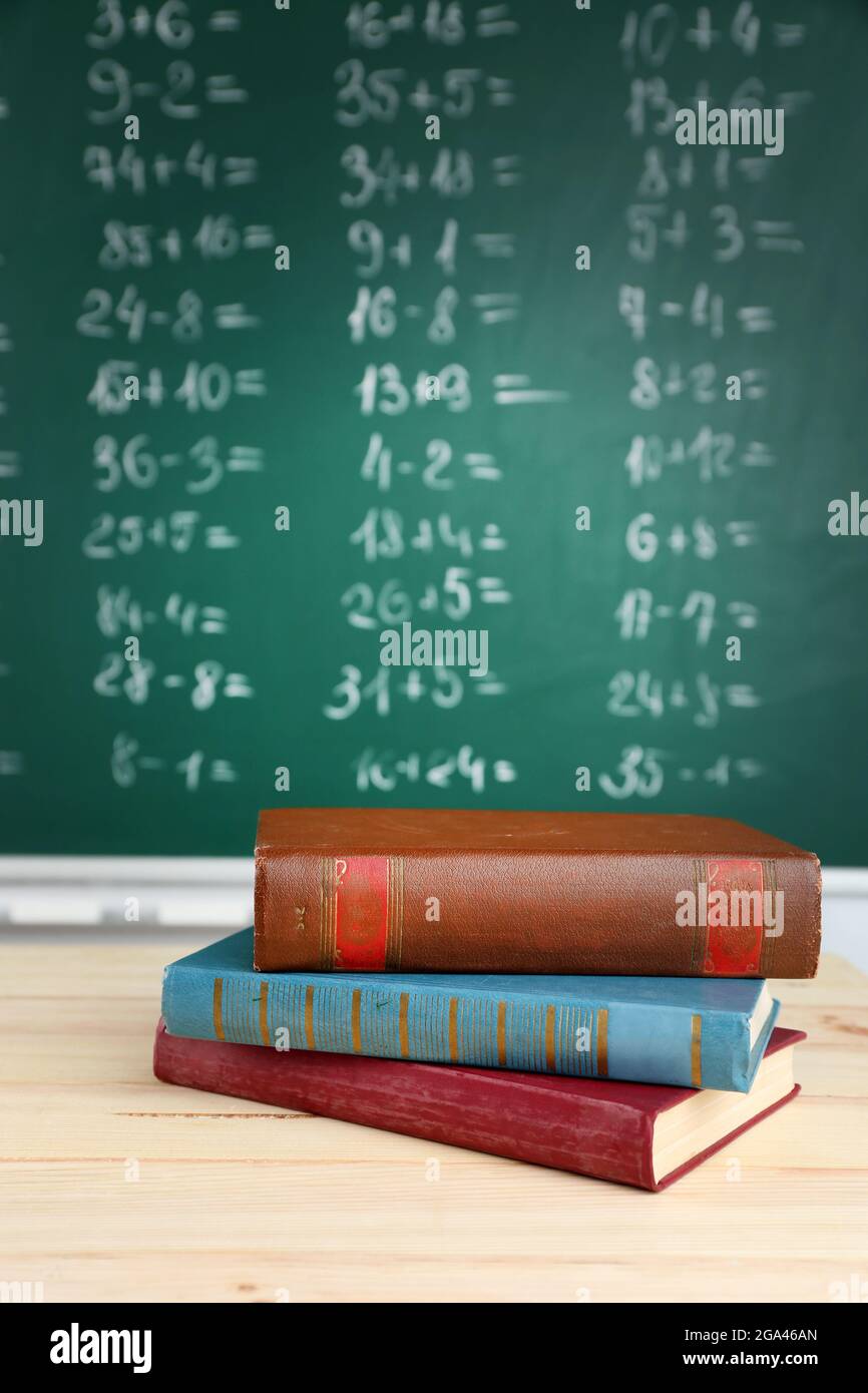 Stack of books on desk, on blackboard background Stock Photo - Alamy