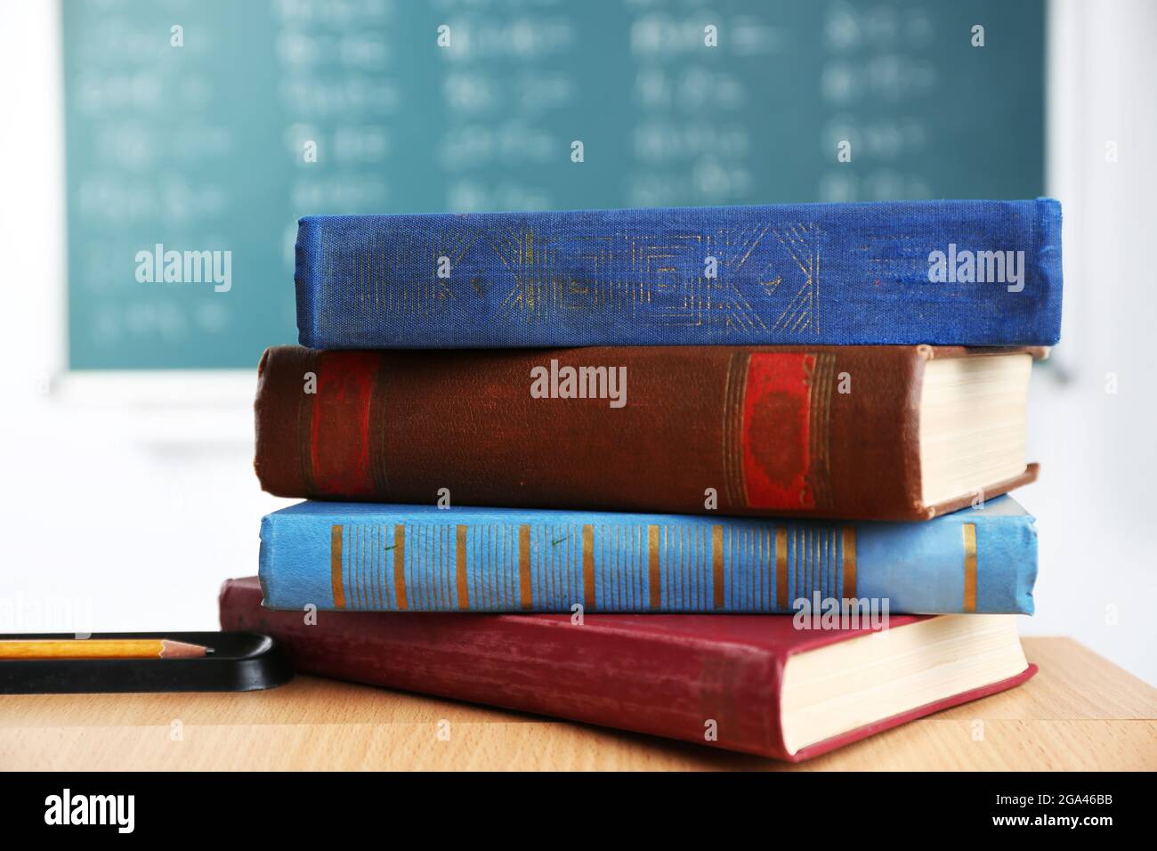 Stack of books on desk, on blackboard background Stock Photo - Alamy