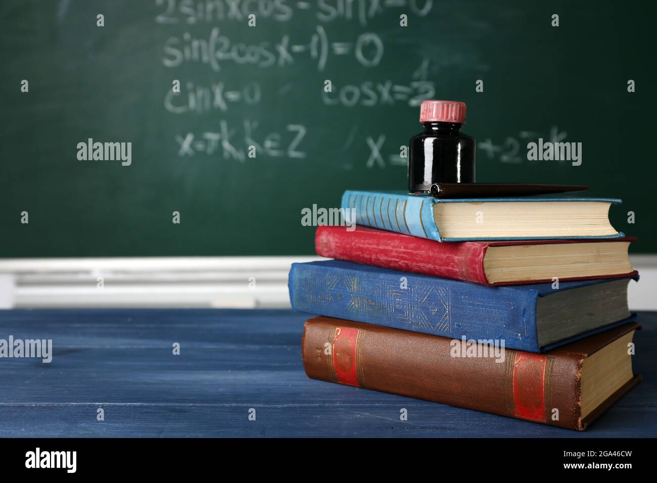 Stack of books on desk, on blackboard background Stock Photo - Alamy