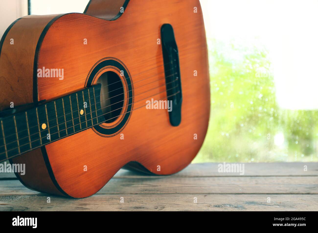 Acoustic guitar next the window with rain drops Stock Photo - Alamy