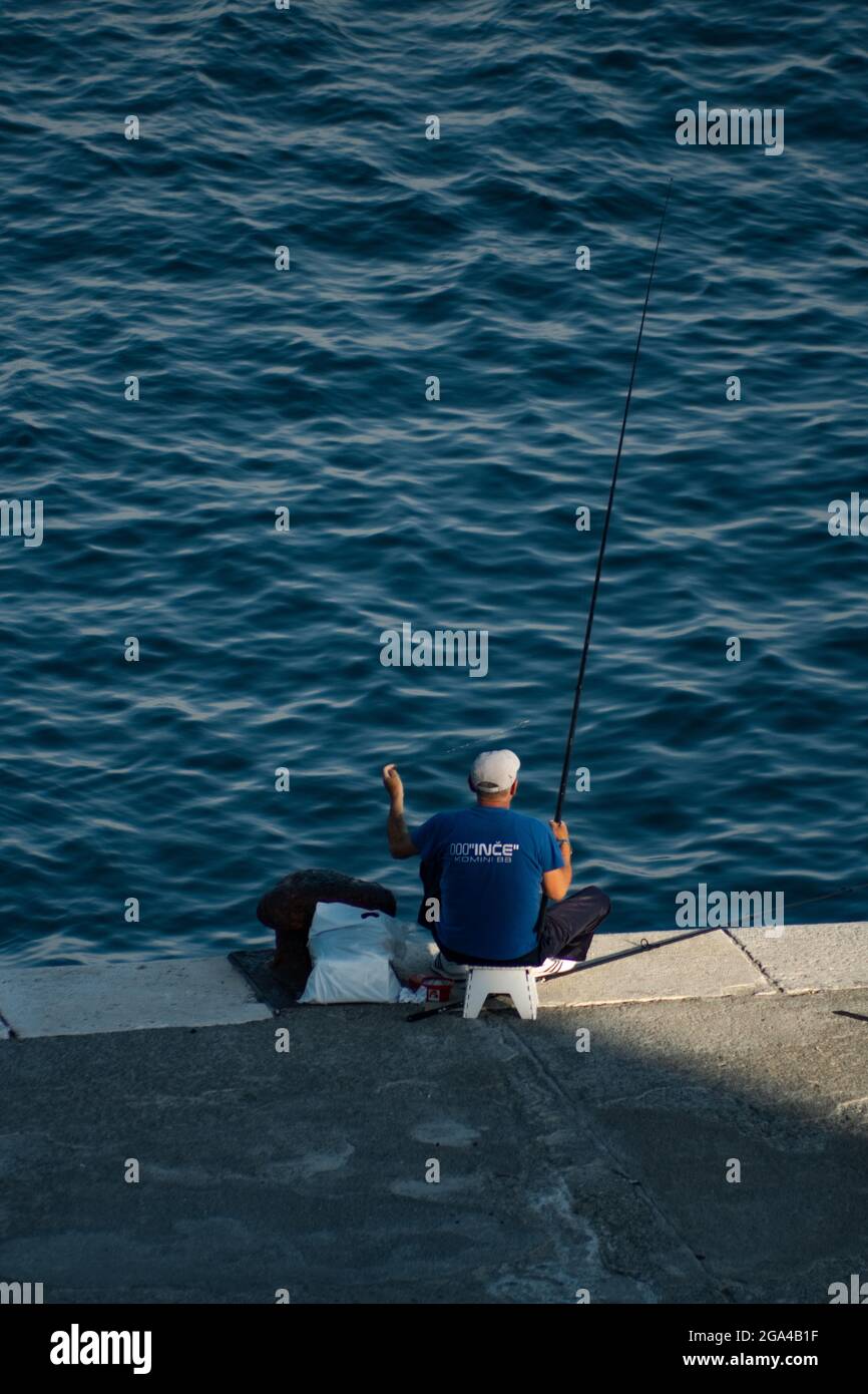 Man sitting down and fishing Stock Photo - Alamy