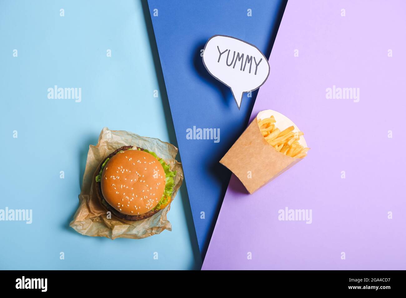 Creative composition with tasty french fries in paper box, burger and ...
