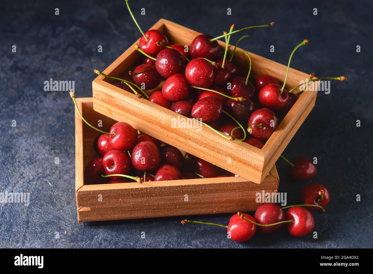 Boxes with sweet cherry on dark background Stock Photo - Alamy