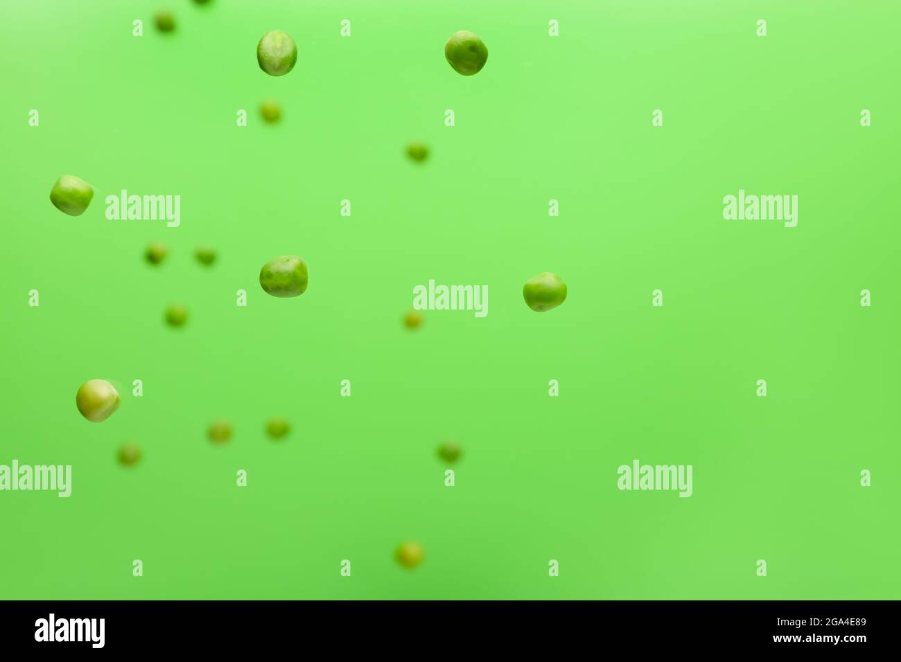 Flying green peas on color background Stock Photo - Alamy
