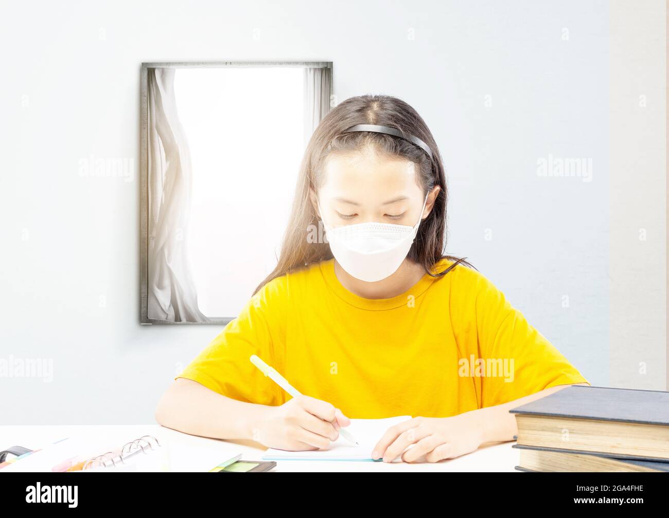 Asian little girl wearing the mask doing her homework at home. Online ...