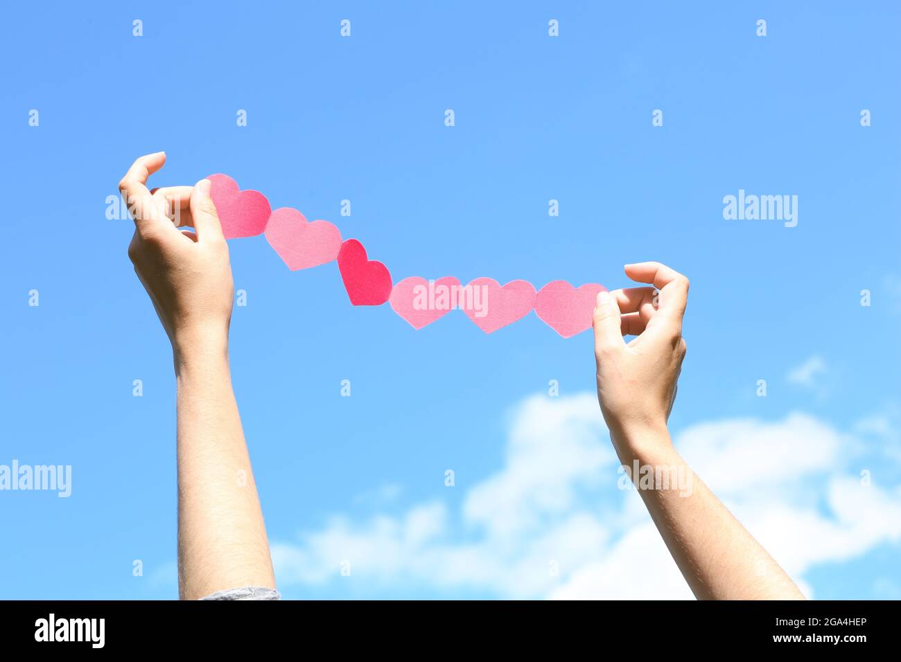 Female hands with chain of paper hearts on blue sky background Stock ...