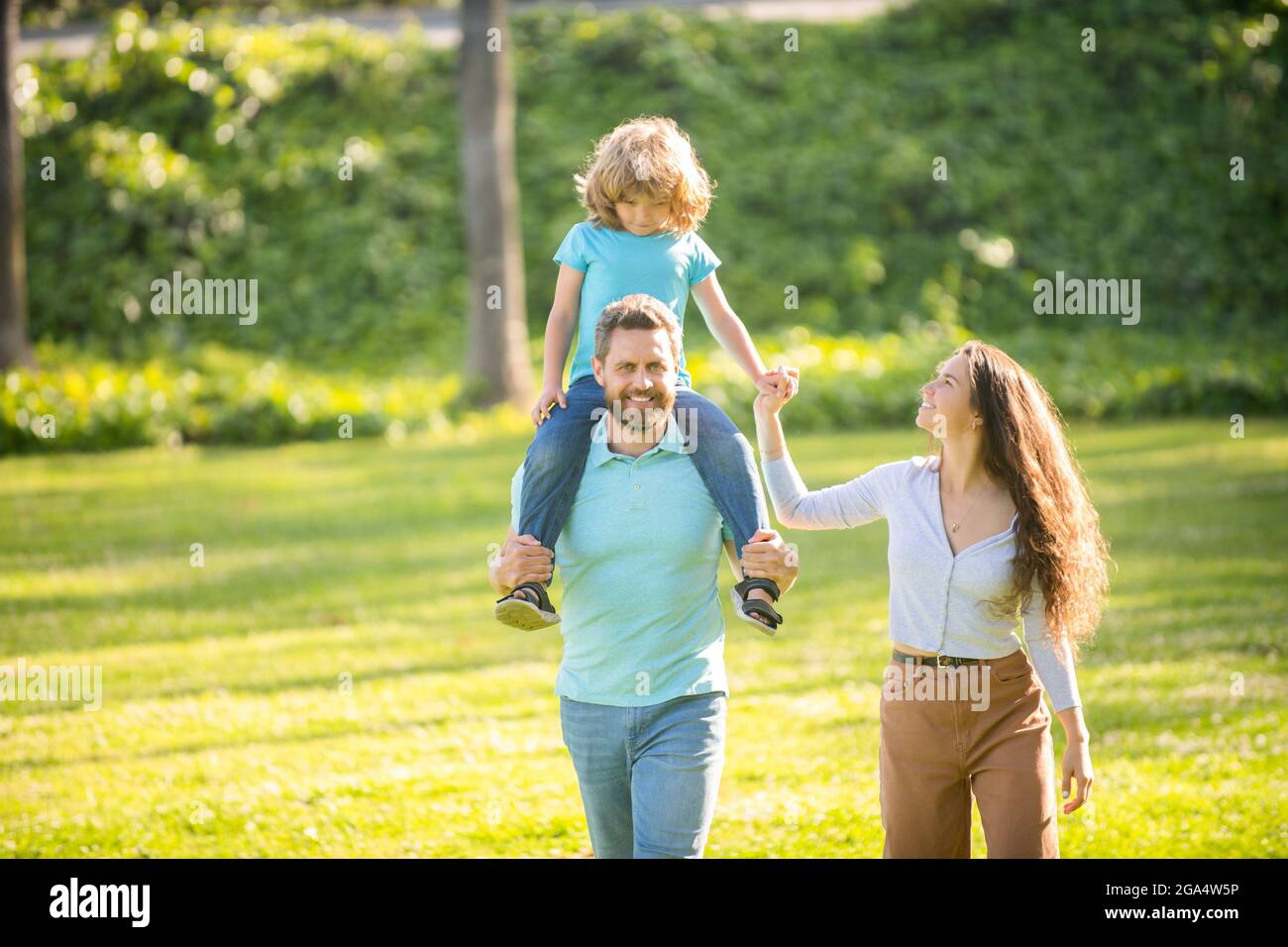 Happy family of mother and father carrying boy child on shoulders ...