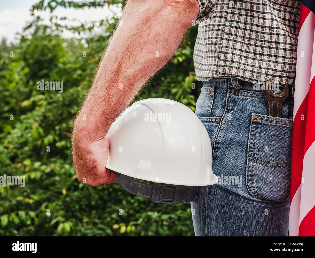 Handsome man holding US Flag and construction helmet against the ...
