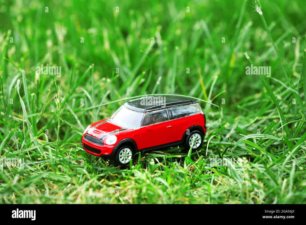 Small car model over green grass background Stock Photo - Alamy