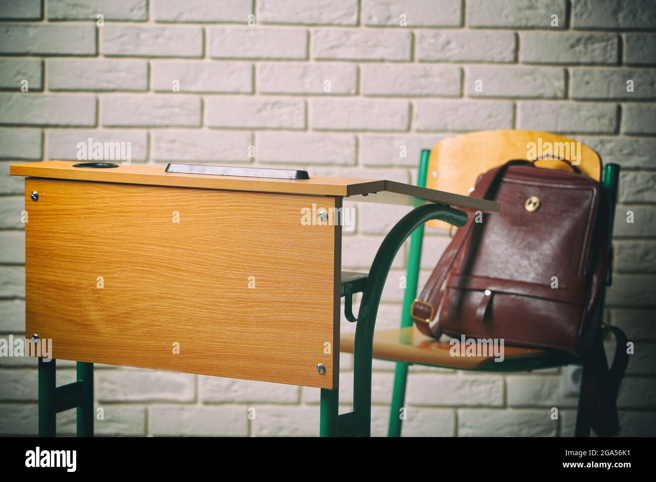 School desk and chair with bag on white brick wall background Stock ...