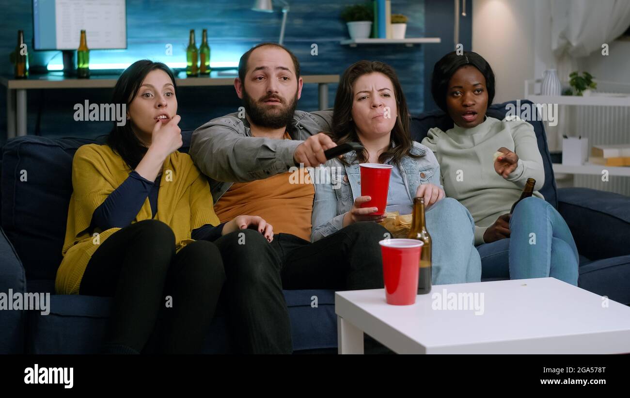 Multi-ethnic friends relaxing on sofa late at night during home party ...