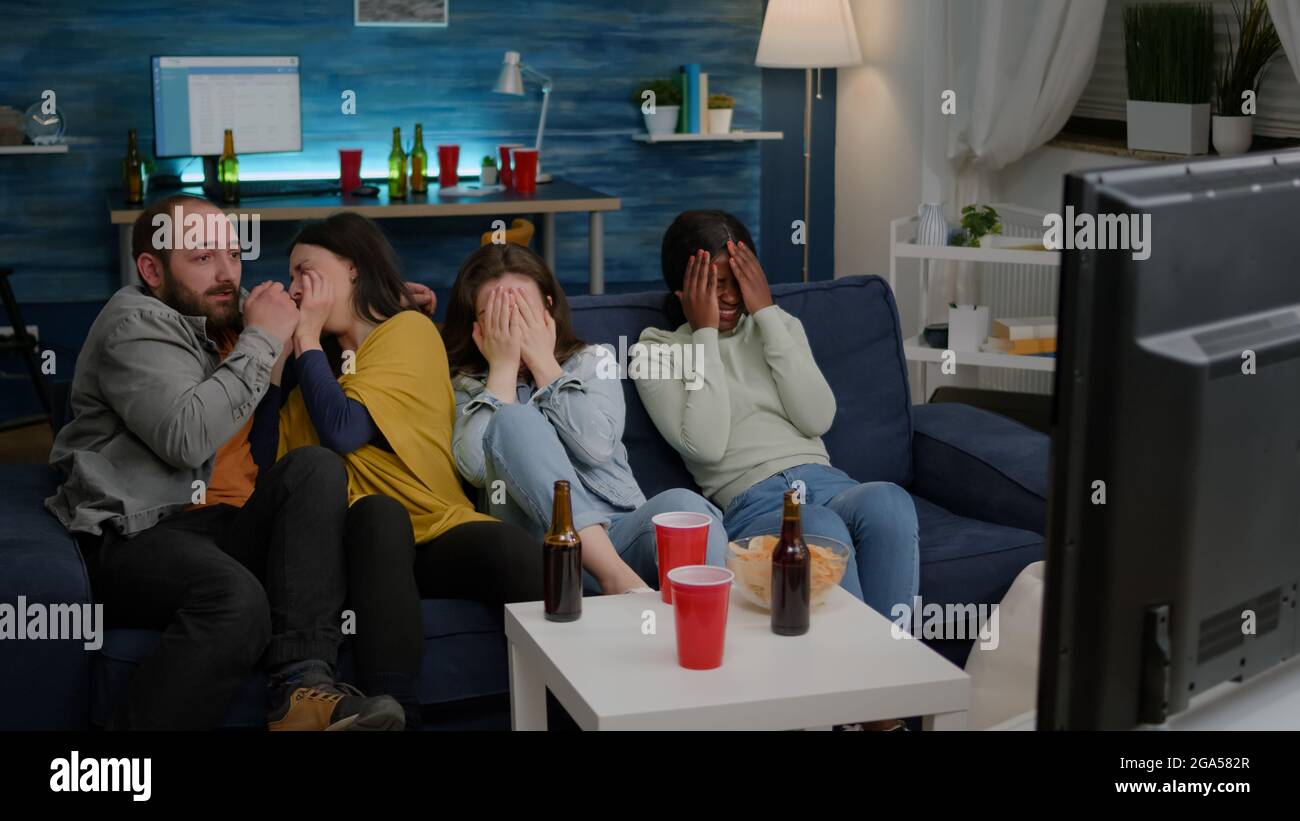 Multi-racial friends screaming while watching thriller horror movie ...