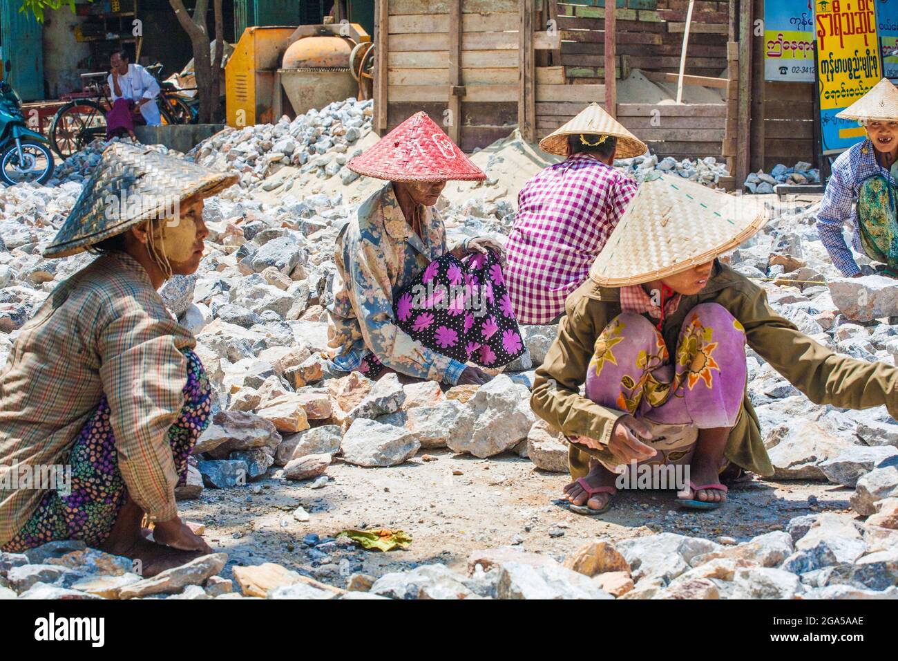 Female road construction workers wearing conical hats breaking large ...