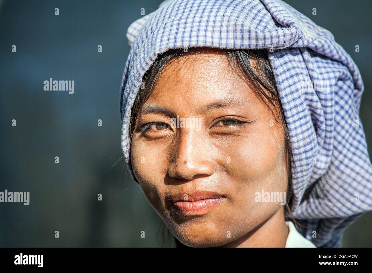 Close up of pretty young Burmese female wearing blue check head wrap ...