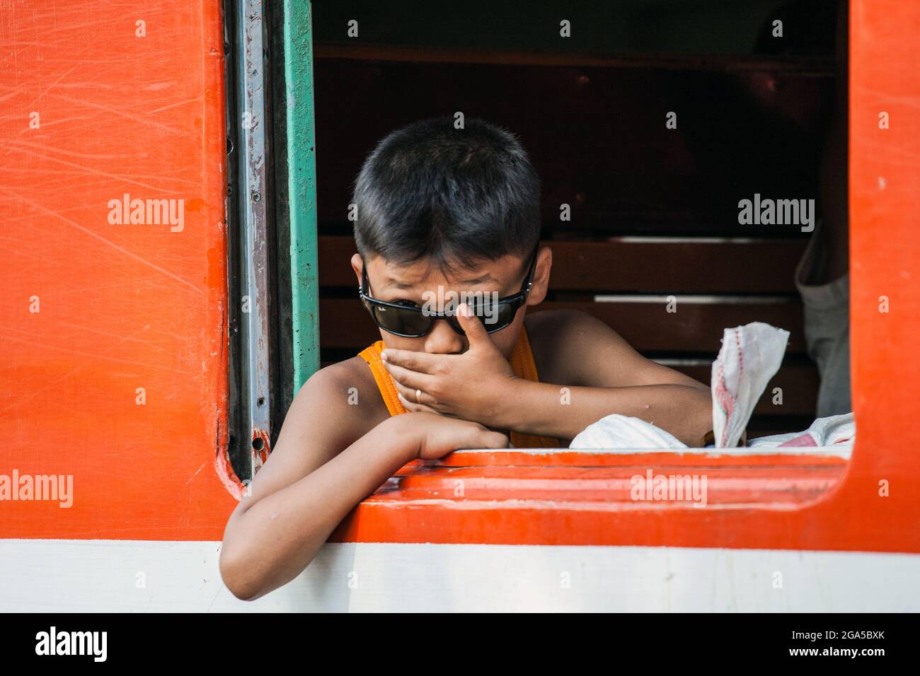 Cute young cool Burmese boy wearing dark sunglasses stares from train ...