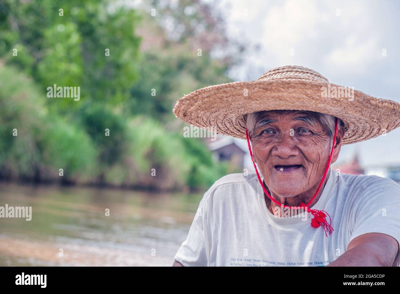 Close up portrait of Burmese boatman with missing teeth wearing straw ...