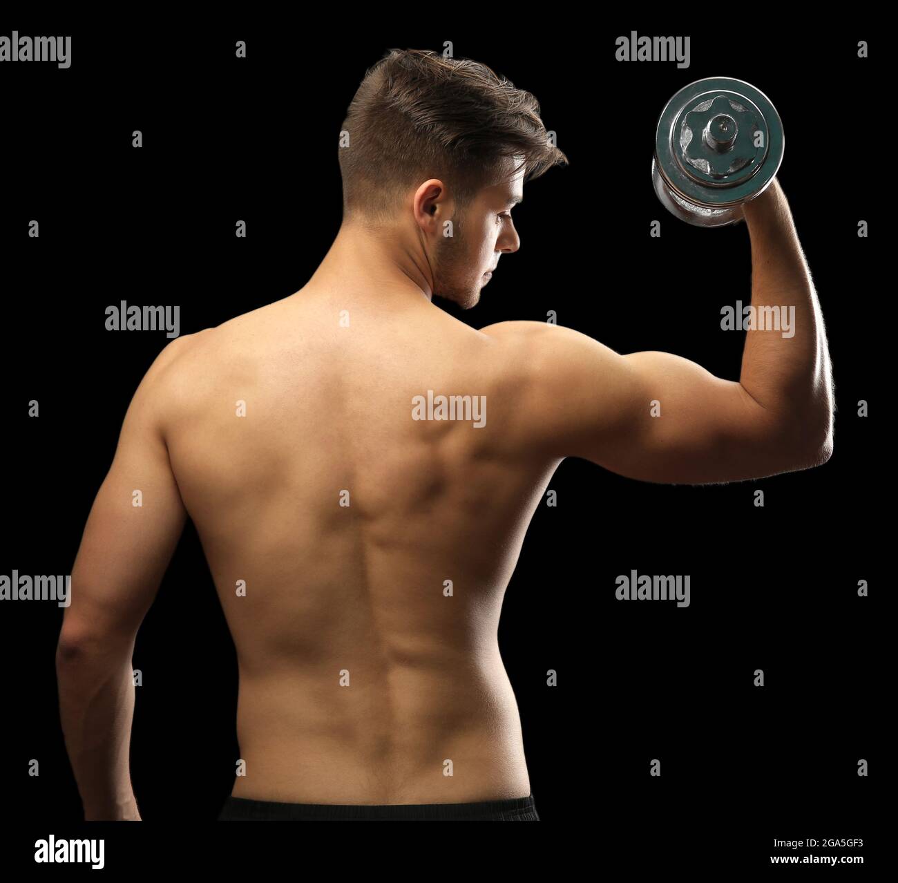 Muscle young man holding dumbbell on dark background Stock Photo - Alamy