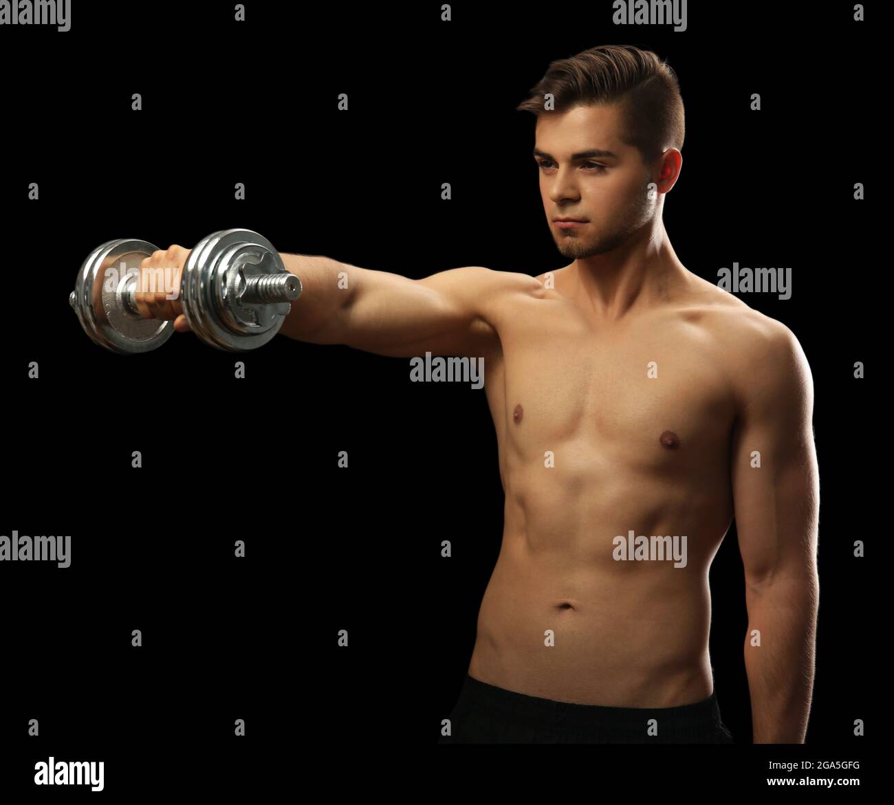Muscle young man holding dumbbell on dark background Stock Photo - Alamy