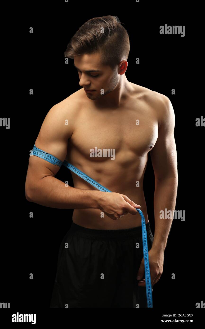 Muscle young man measuring muscle on dark background Stock Photo - Alamy