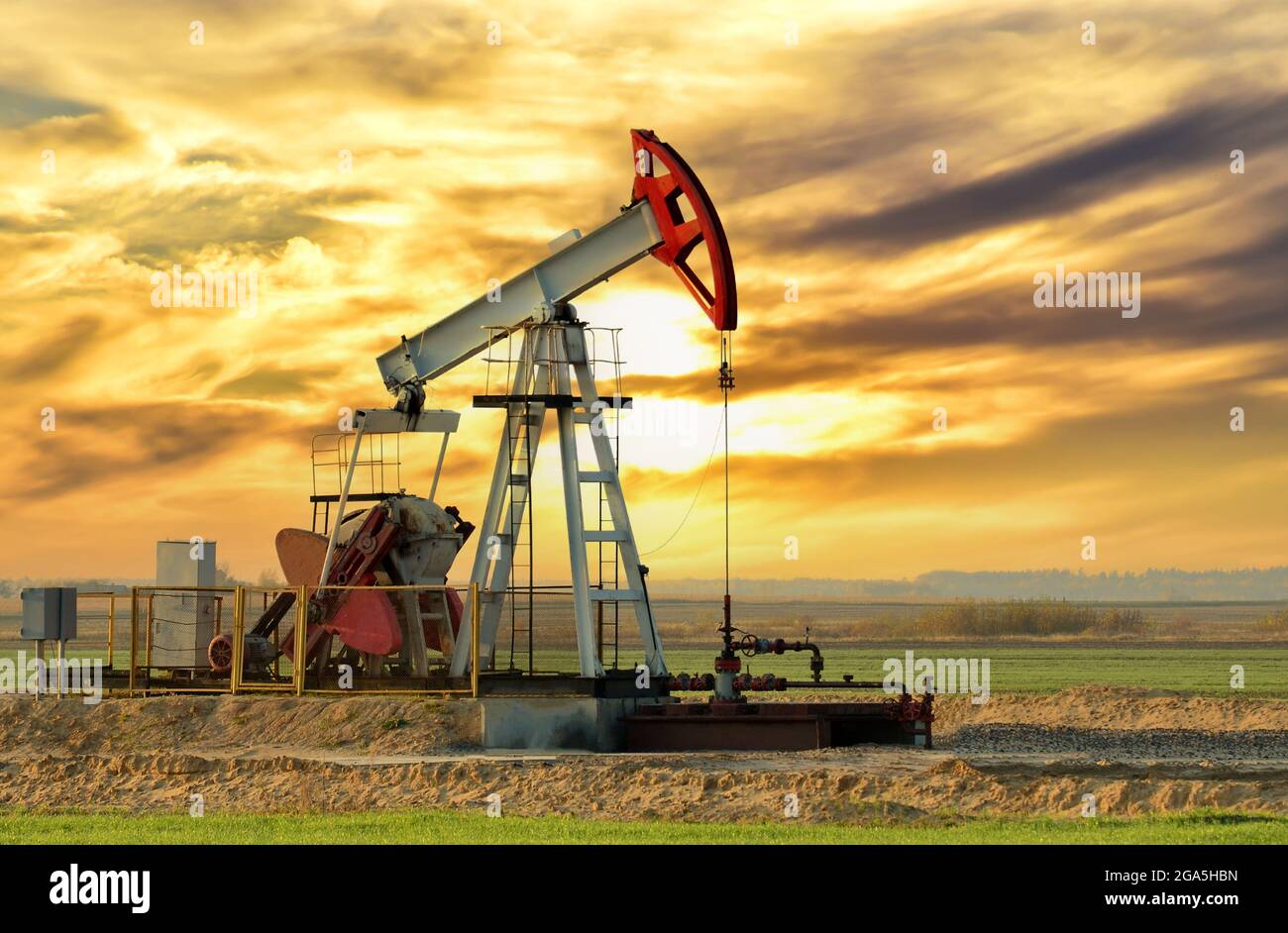 Crude oil pump jack at oilfield on sunset backround. Fossil crude output and fuels oil ...